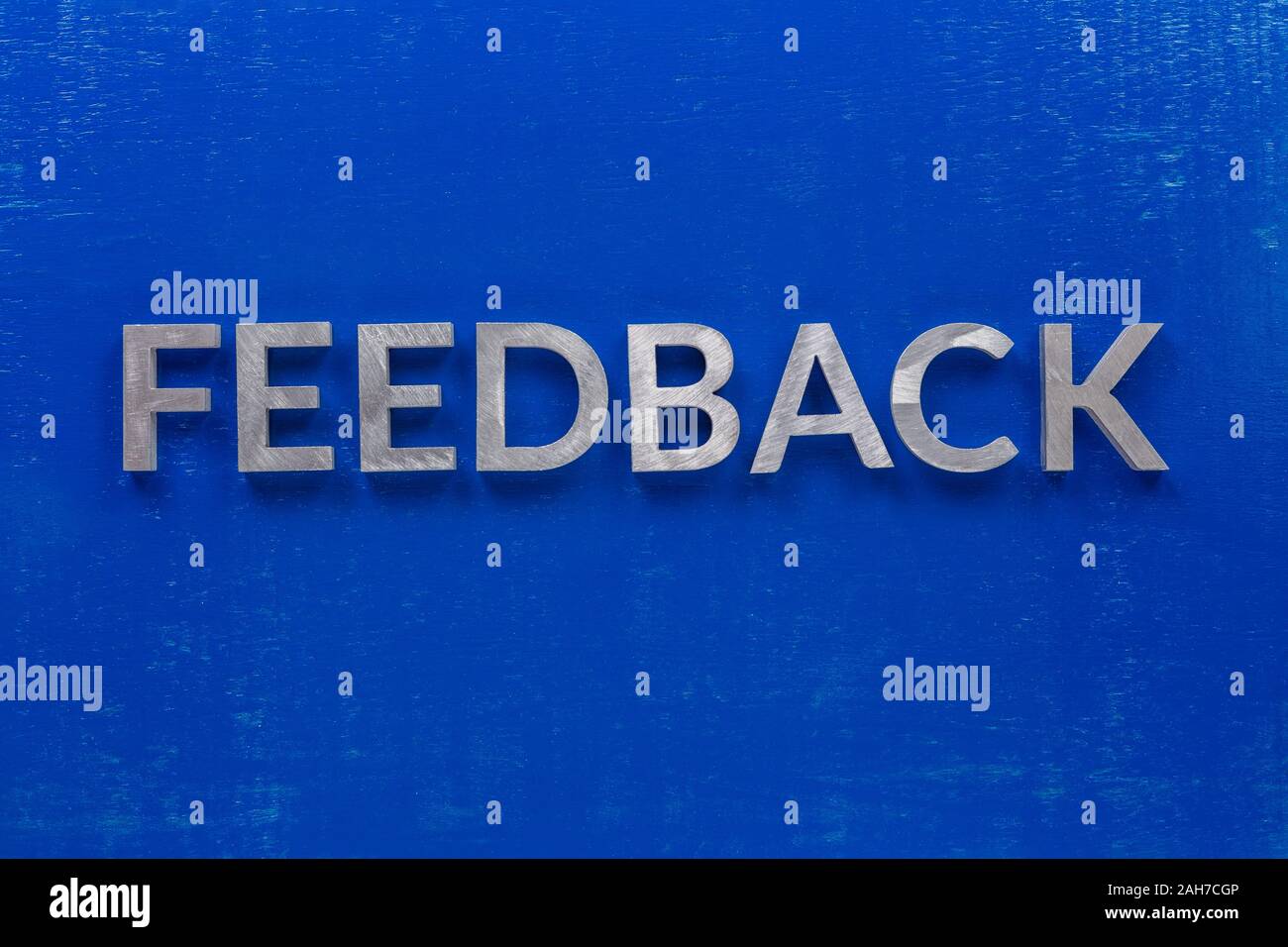 The word feedback laid on blue painted board with thick silver metal ...
