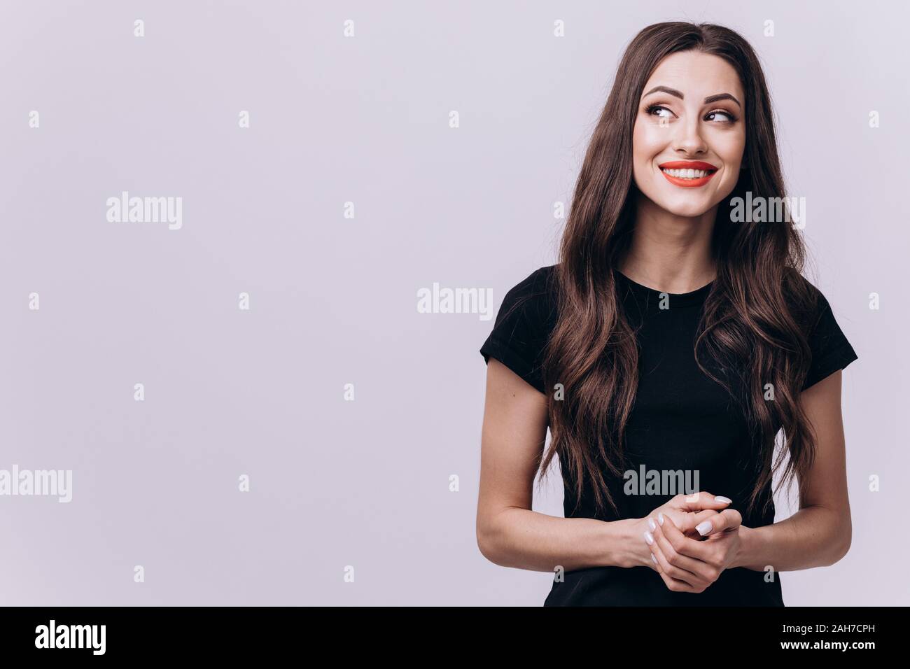 Cute smiling brunette model giving a sly look aside isolated light ...