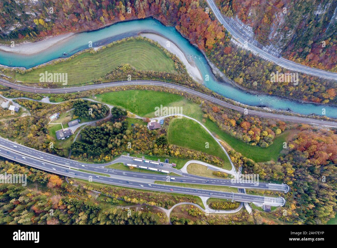 Top dawn aerial view of freeway speed road going out from undeground tunnel between yellow ...