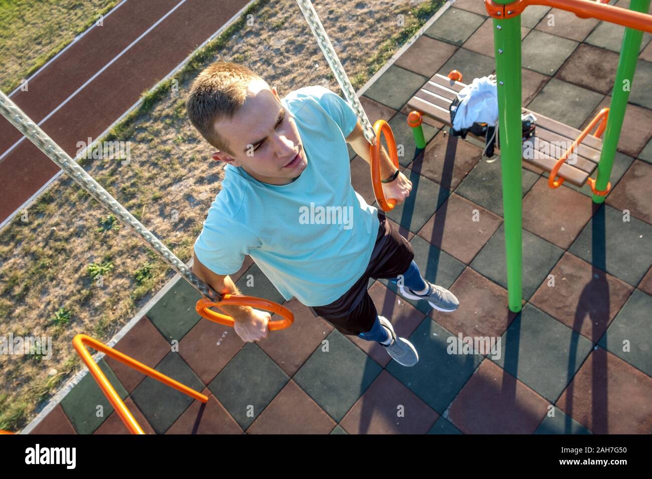 Young fit athlete working out at outdoor gym making dipping pull ups ...