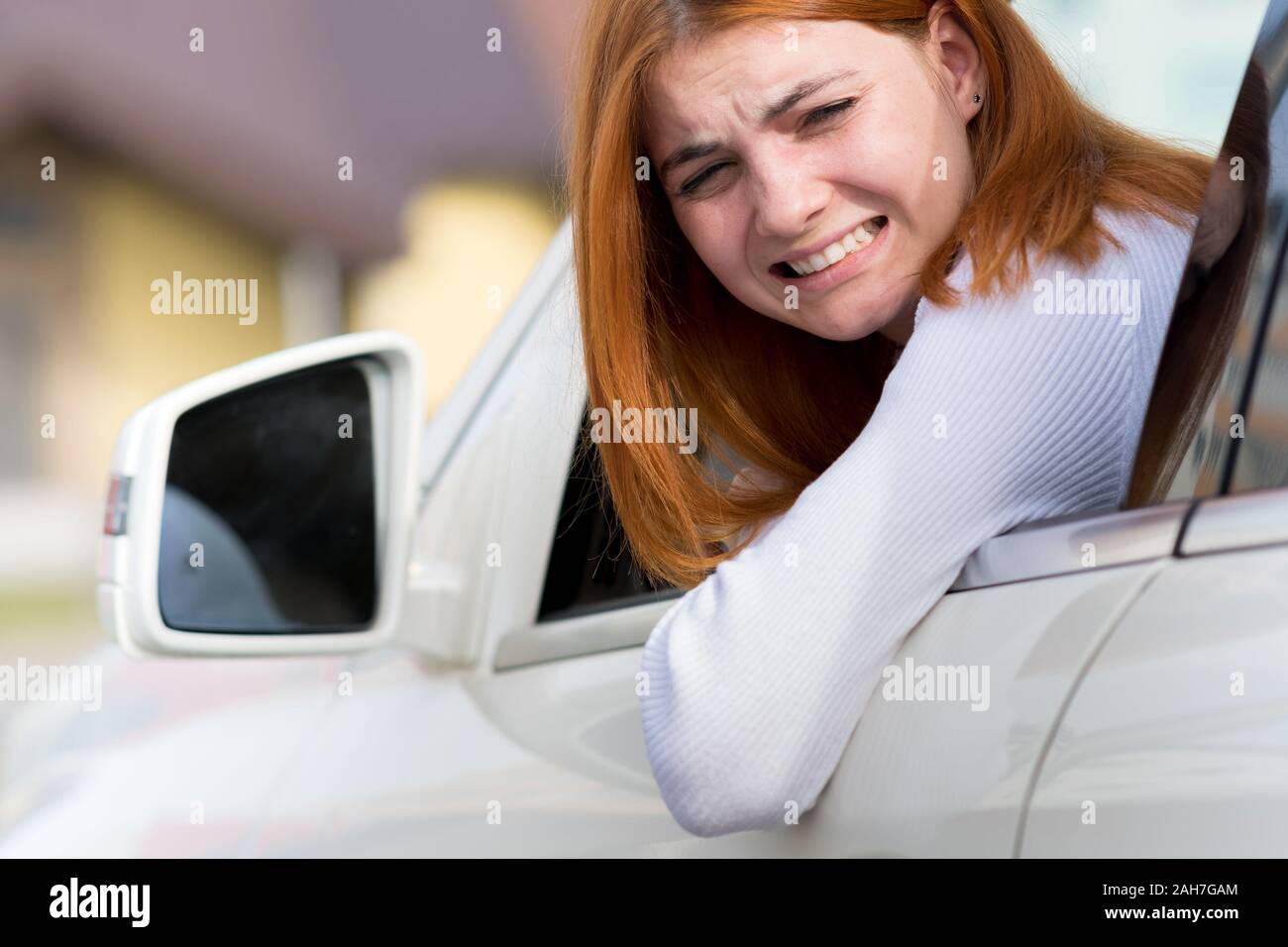 Young woman driving a car backwards. Girl with funny expression on her ...