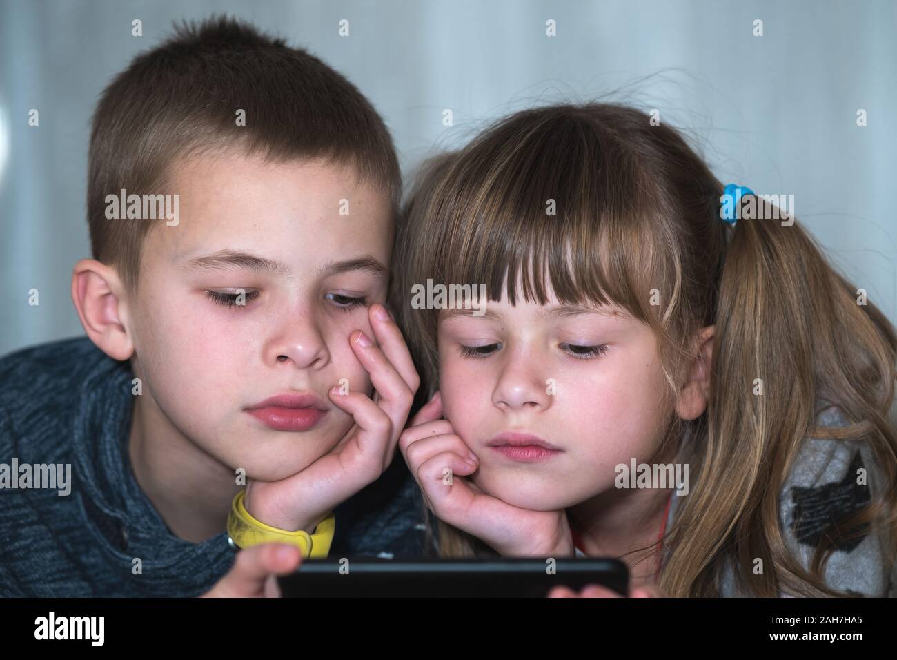 Two children brother and sister watching video on smartphone screen ...