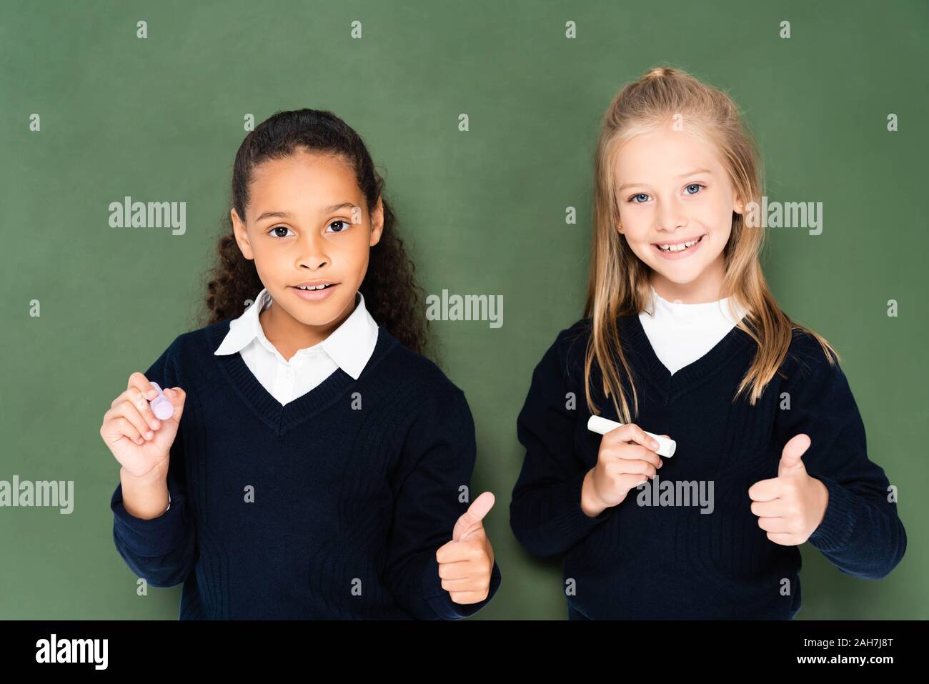 adorable multicultural schoolgirls showing thumbs up and looking at ...