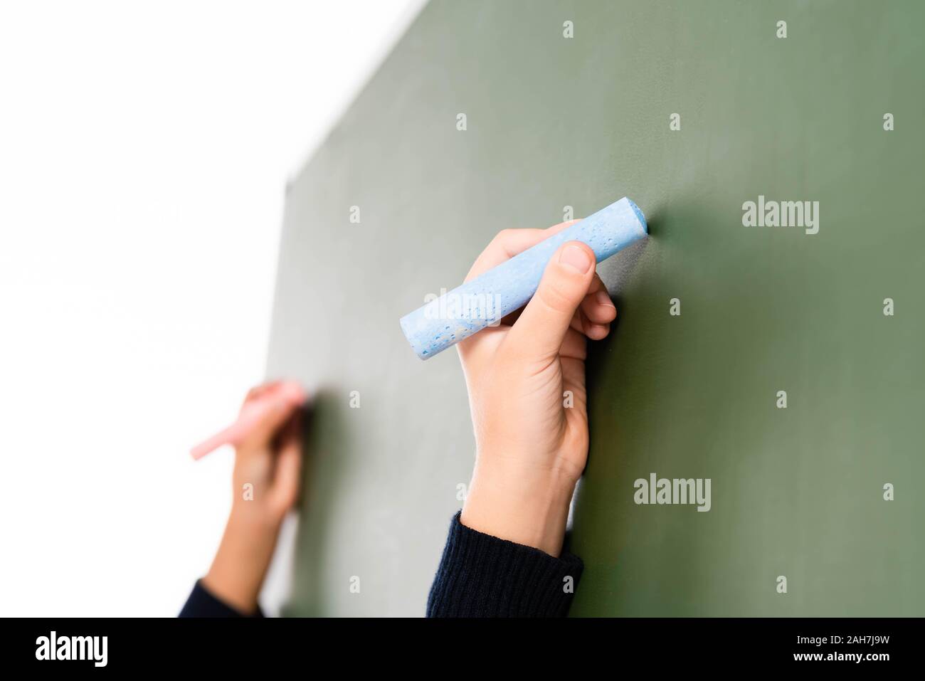 parftial view of two multicultural schoolgirls writing on chalkboard ...