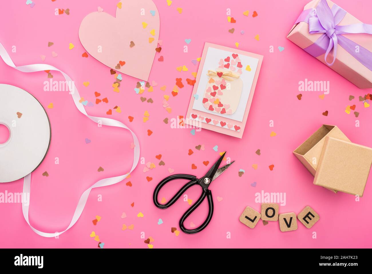 top view of valentines confetti, empty compact disk, scissors, gift ...