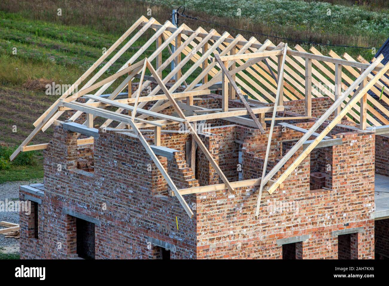 Unfinished brick house with wooden roof structure under construction ...