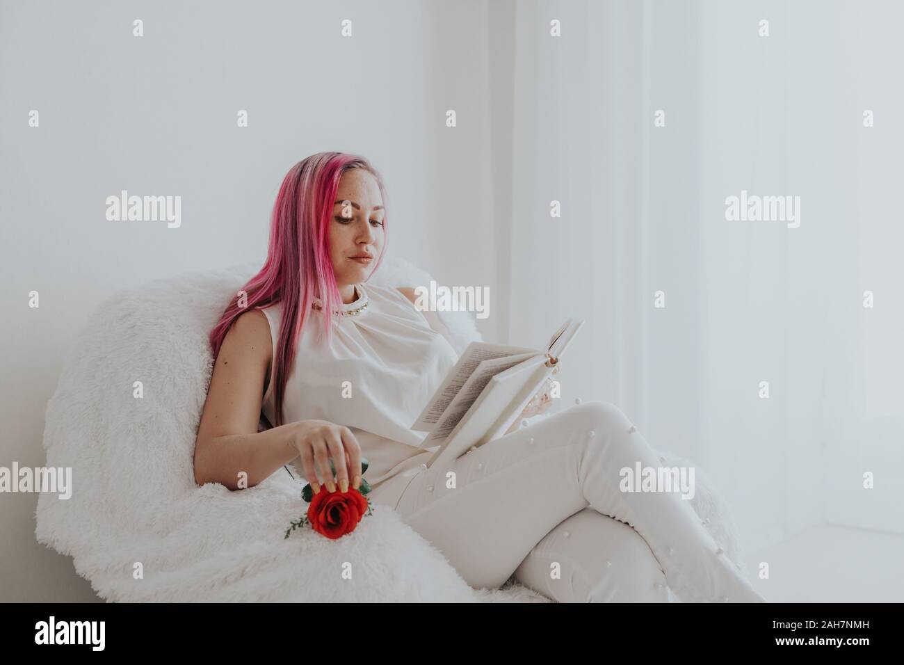beautiful woman with pink hair reading a book in a white room Stock ...