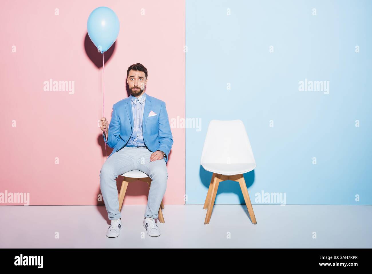 handsome and sad man holding balloon on blue and pink background Stock ...
