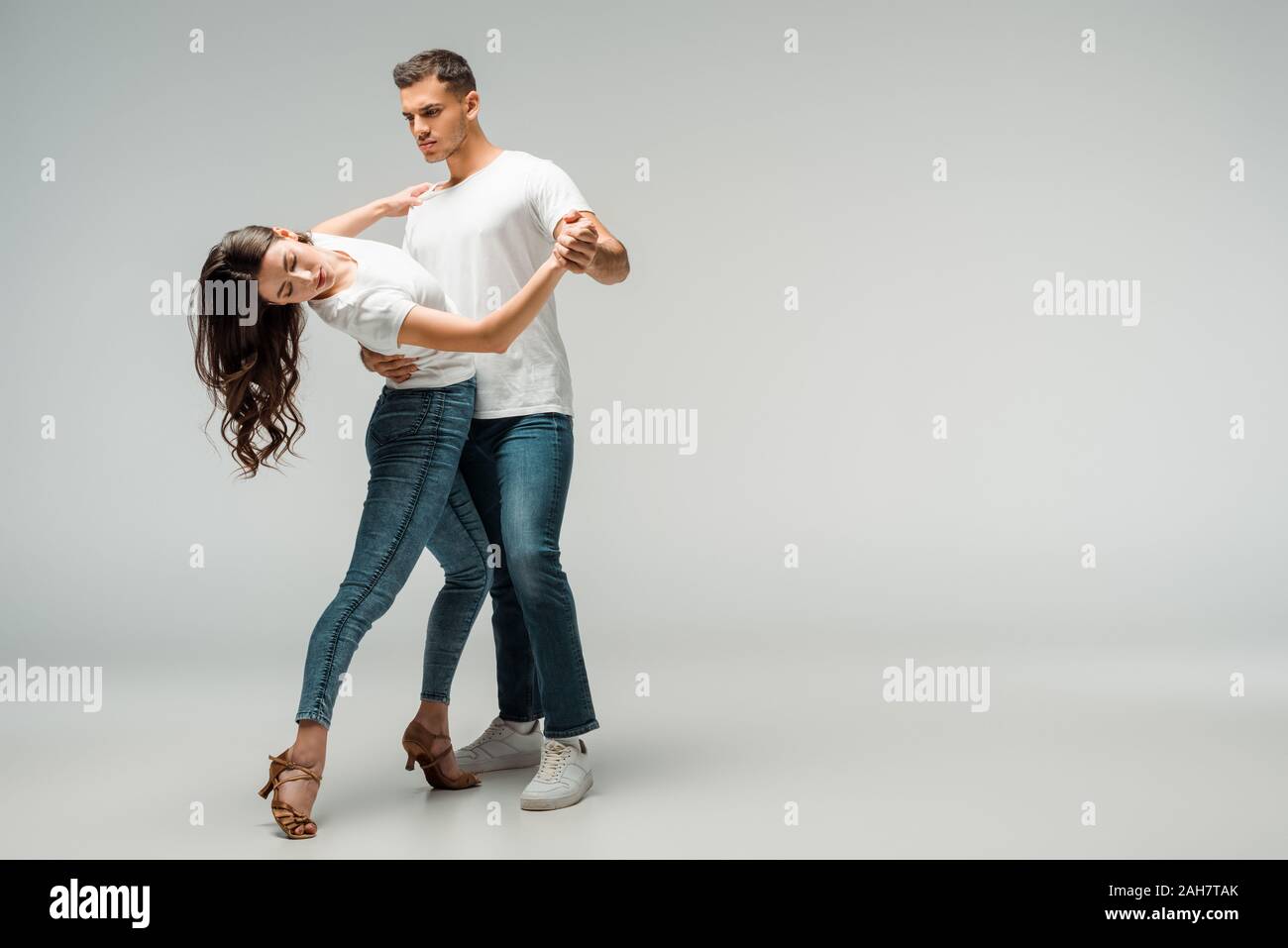 dancers in t-shirts and jeans dancing bachata on grey background Stock ...