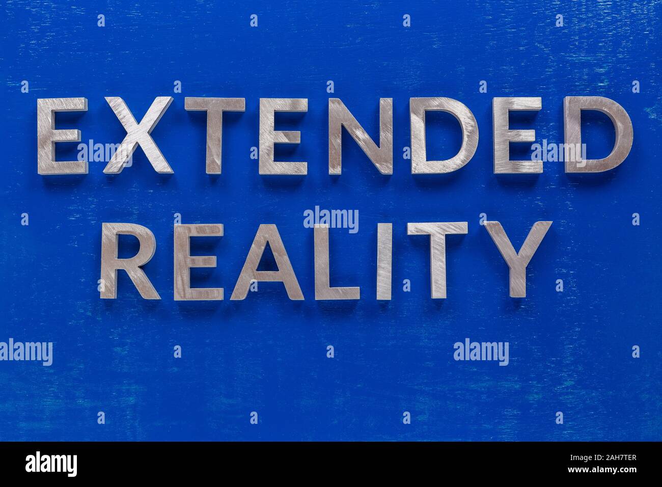 The words extended reality laid on blue painted board with thick silver ...
