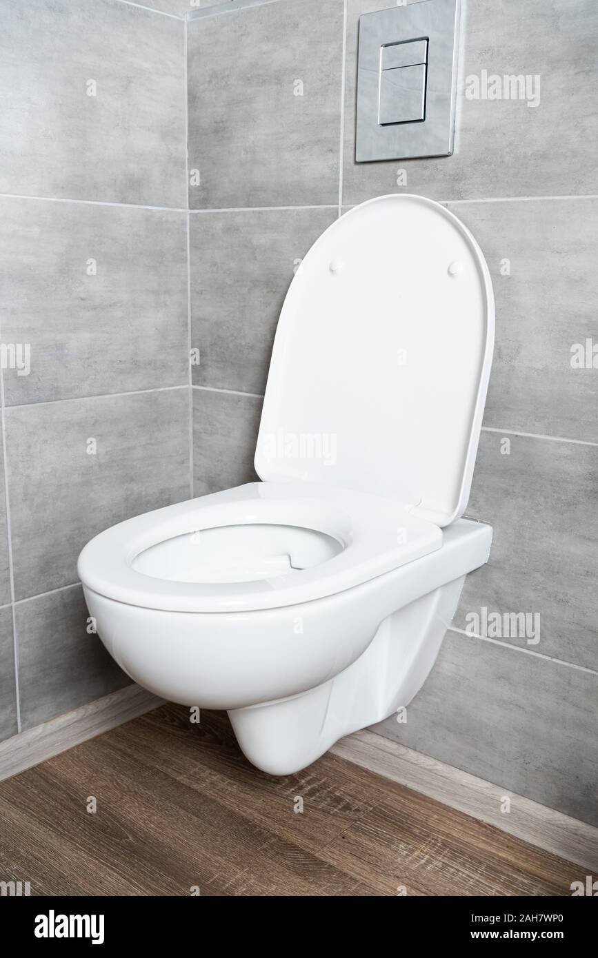 White toilet bowl with open seat in restroom with grey tile Stock Photo ...