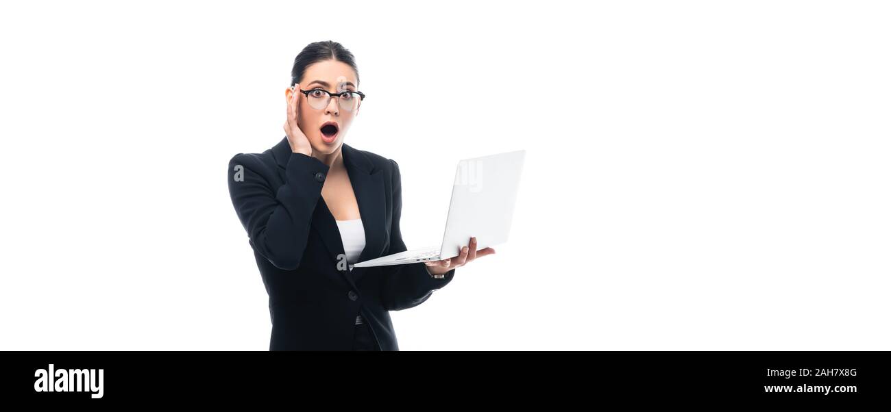 panoramic shot of shocked businesswoman holding laptop while looking at ...