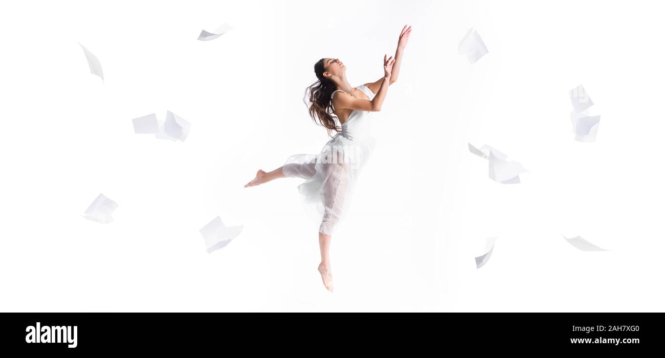 panoramic shot of dancing ballerina surrounded with flying papers ...