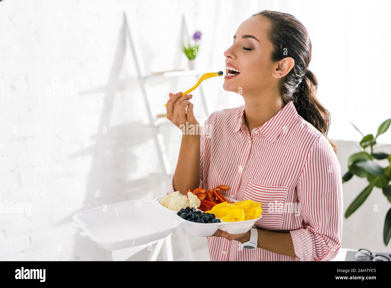 happy girl with closed eyes eating blueberry Stock Photo - Alamy