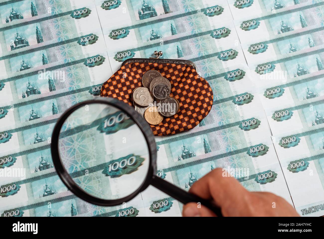 selective focus of man holding magnifying glass near coins on plaid ...