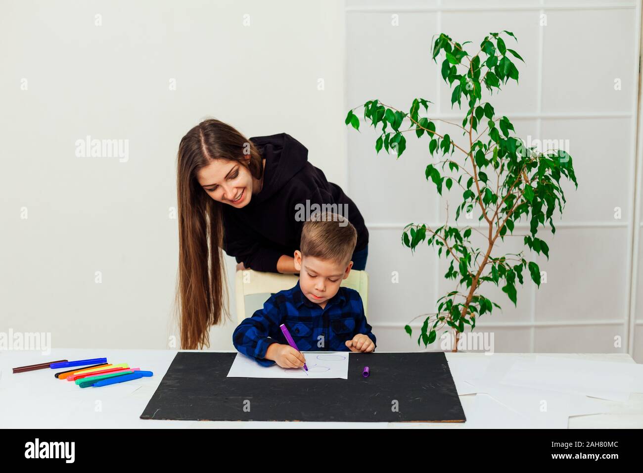 female teacher teaches a little boy to draw at the table Stock Photo ...