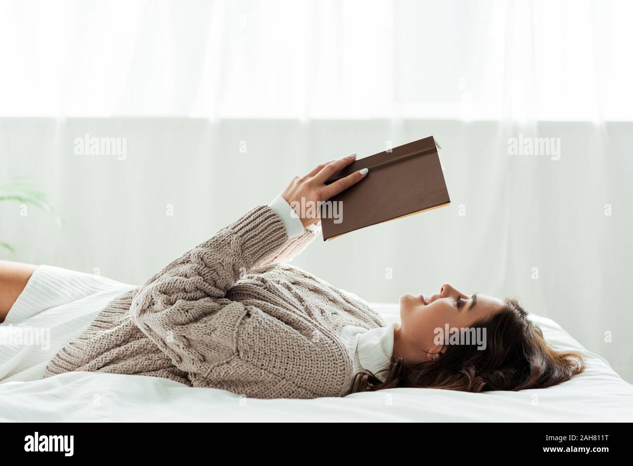 panoramic shot of attractive woman in grey sweater reading book at ...