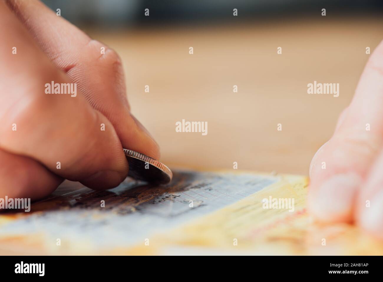 selective focus of silver coin in hand of gambler scratching lottery ...