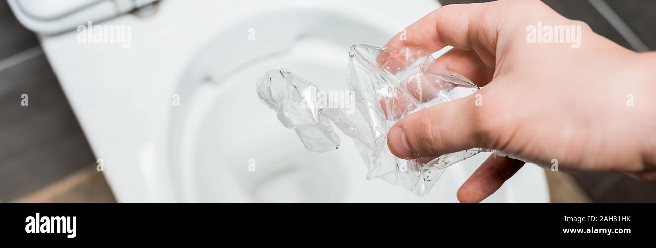 cropped view of man throwing crumpled plastic bottle in toilet bowl in ...