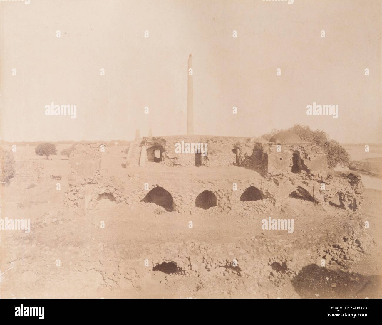 India, Ruins in Delhi: a stone monolith next to crumbling city walls ...