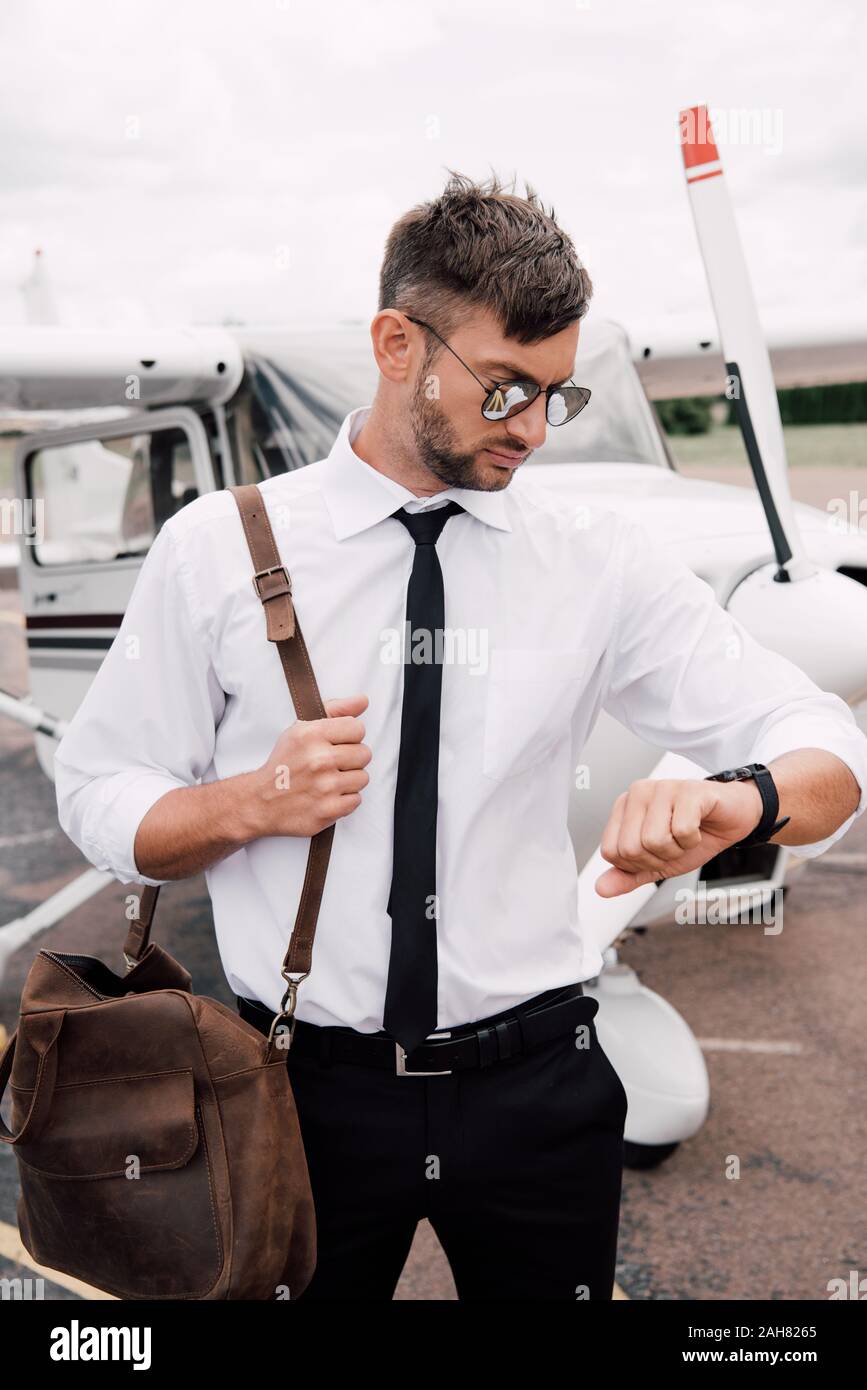 bearded pilot in sunglasses standing near plane and looking at ...