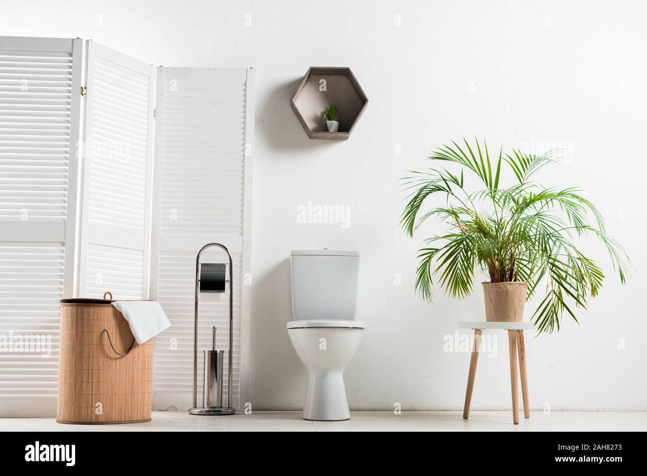 interior of white modern bathroom with toilet bowl near folding screen ...