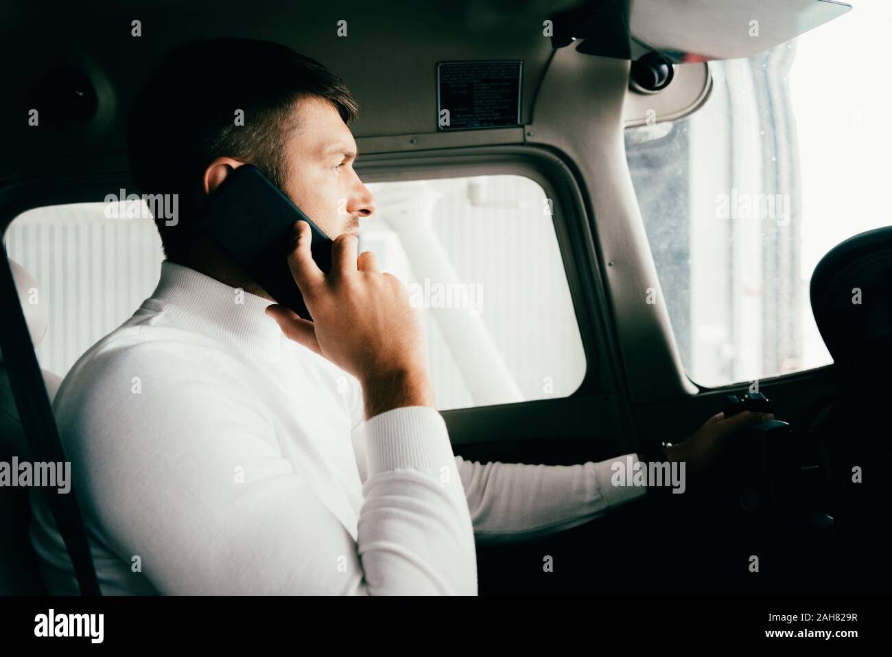 side view of pilot talking on smartphone in plane Stock Photo - Alamy