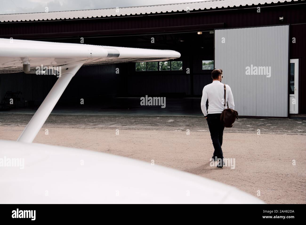 back view of man with bag walking near plane Stock Photo - Alamy