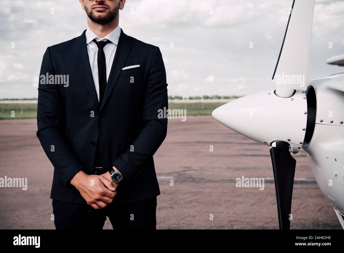 partial view of confident businessman in formal wear standing near ...