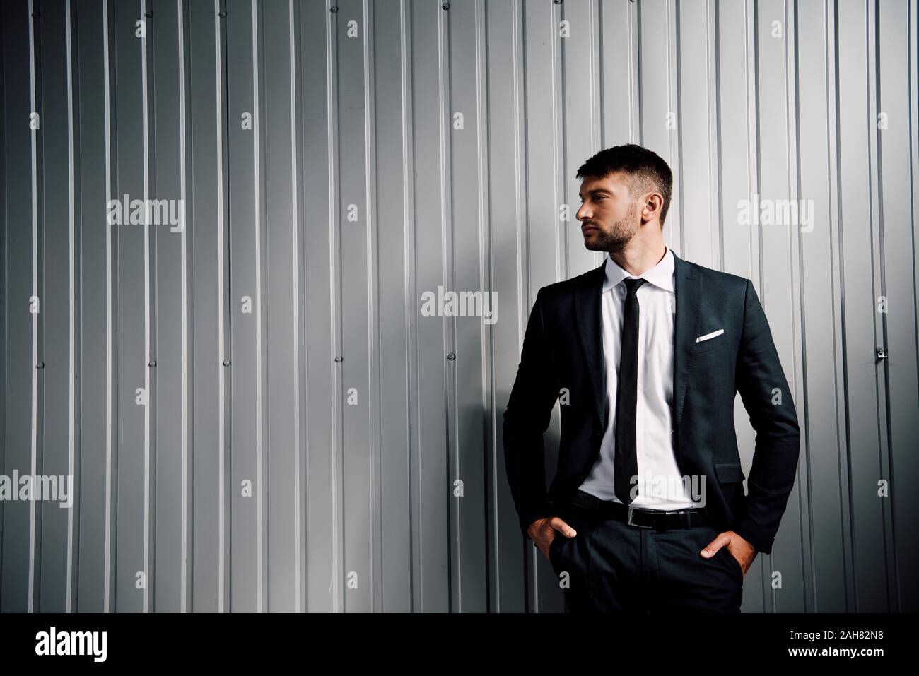 confident businessman in formal wear standing with hands in pockets ...