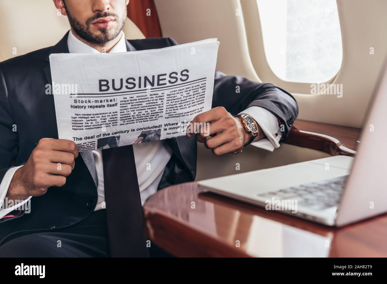 cropped view of businessman in suit reading business newspaper in ...