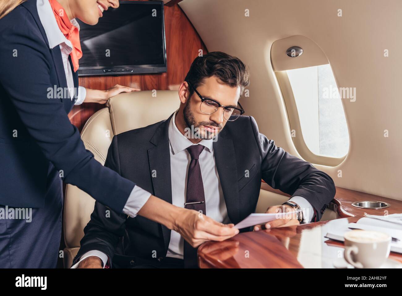 cropped view of flight attendant giving menu to handsome businessman in ...