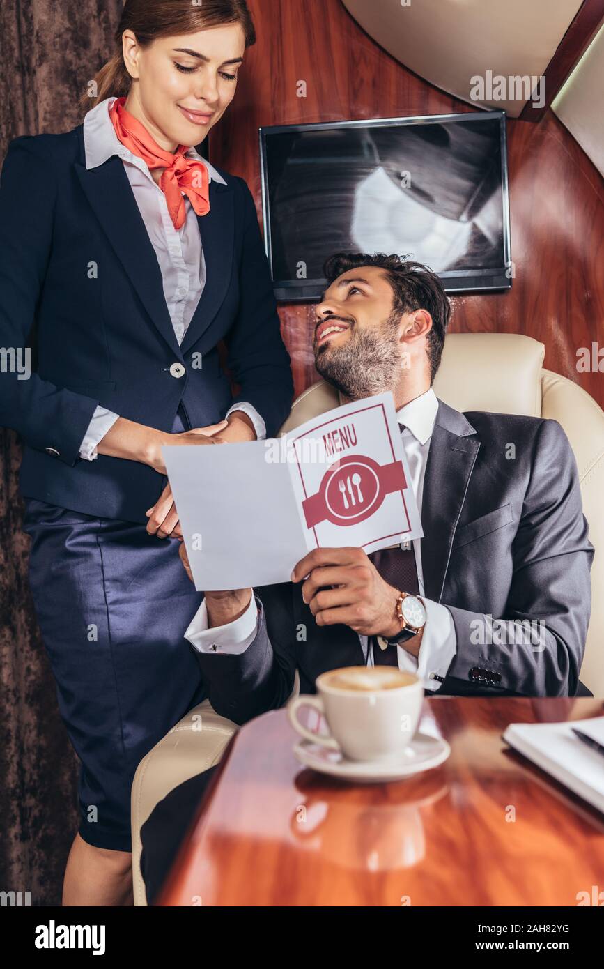 handsome businessman in suit holding menu and talking with flight ...