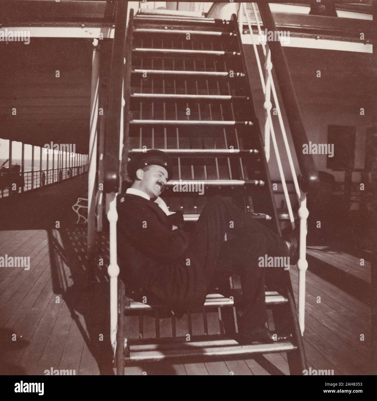 A passenger aboard the S.S. Balmoral Castle sits on steps leading to ...