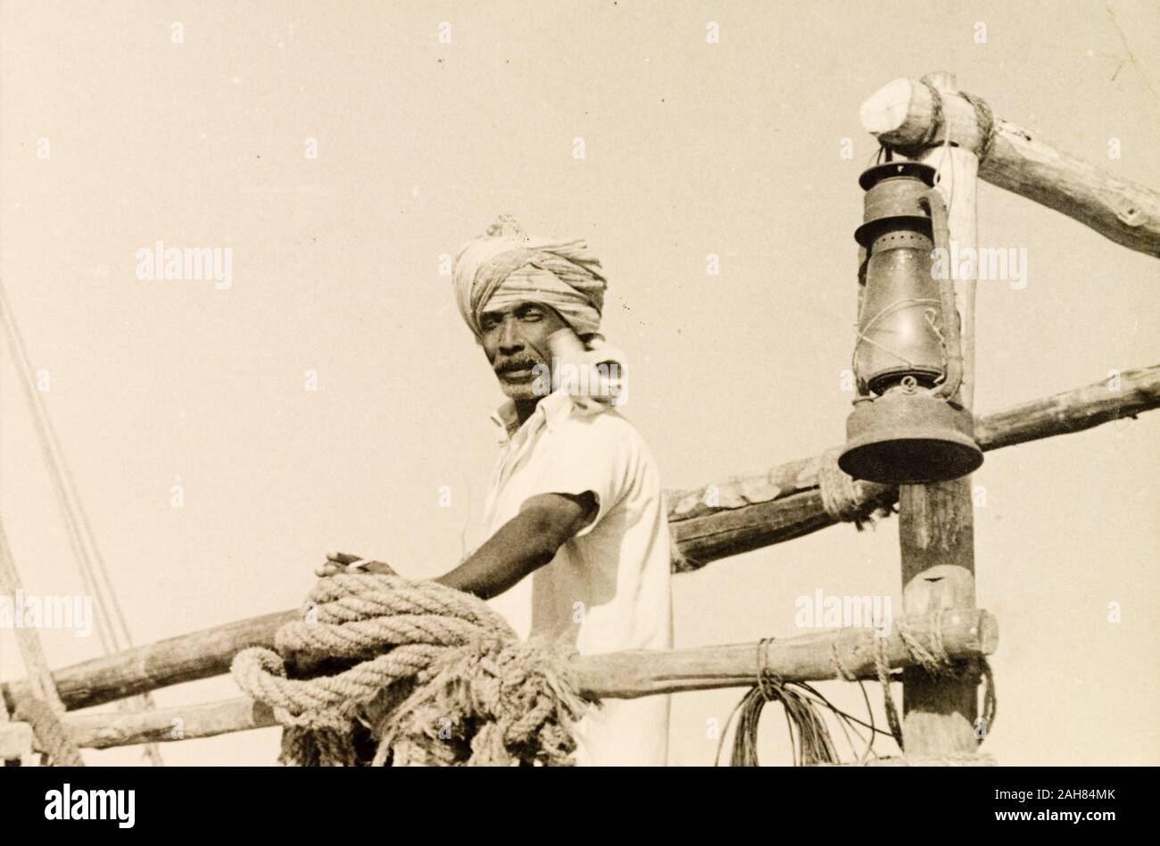 Kenya, A turbaned dhow captain stands on the deck of his boat with a ...