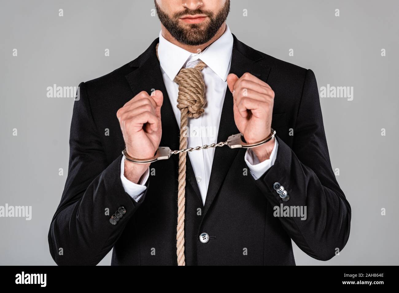 cropped view of businessman in black suit and handcuffs with noose on ...