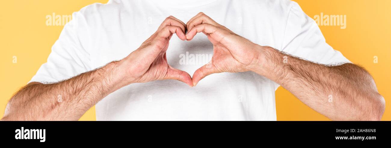 cropped view of man in white t-shirt showing heart sign with hands ...