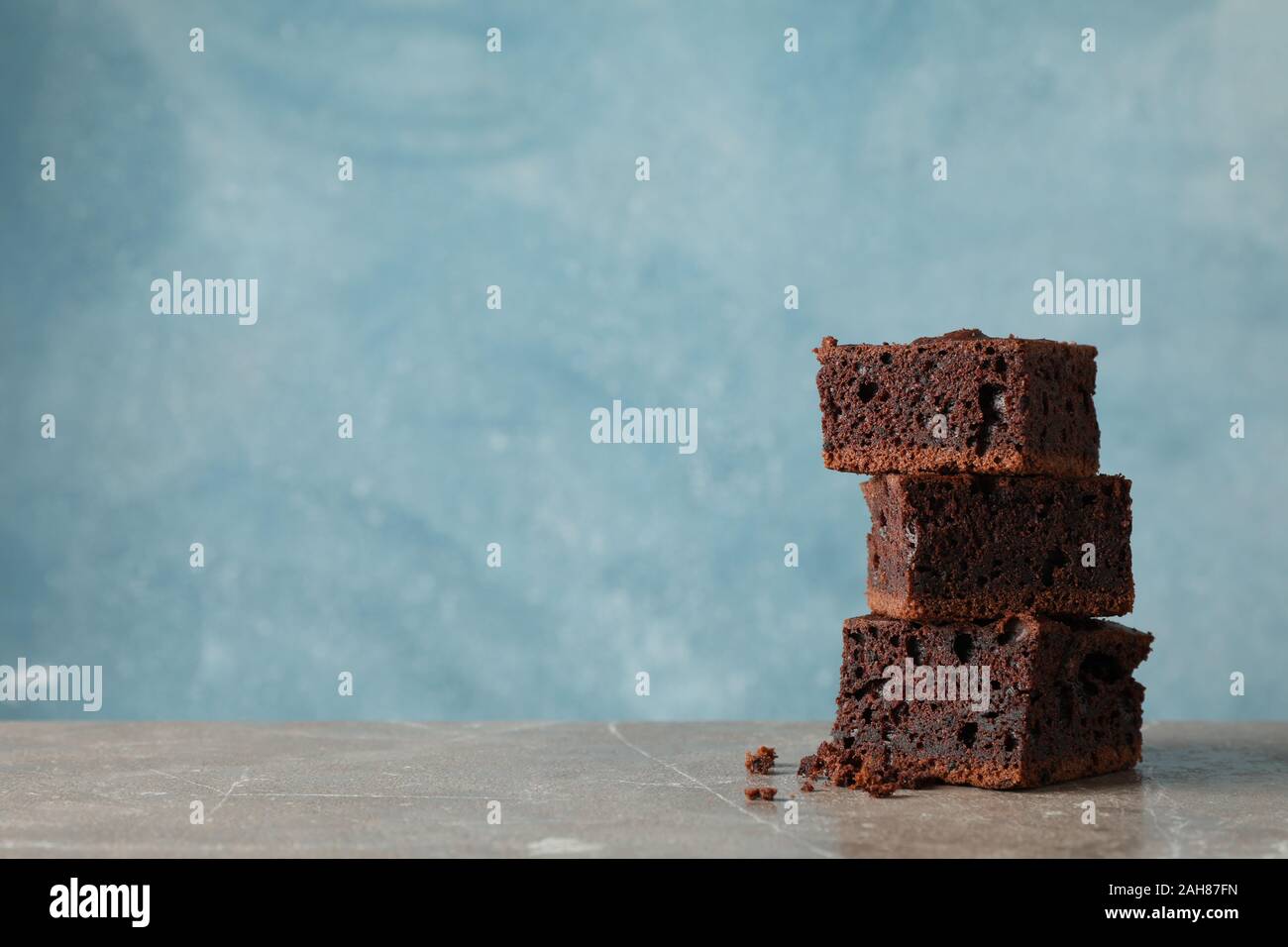 Pile of delicious chocolate cake slices on grey table, space for text ...