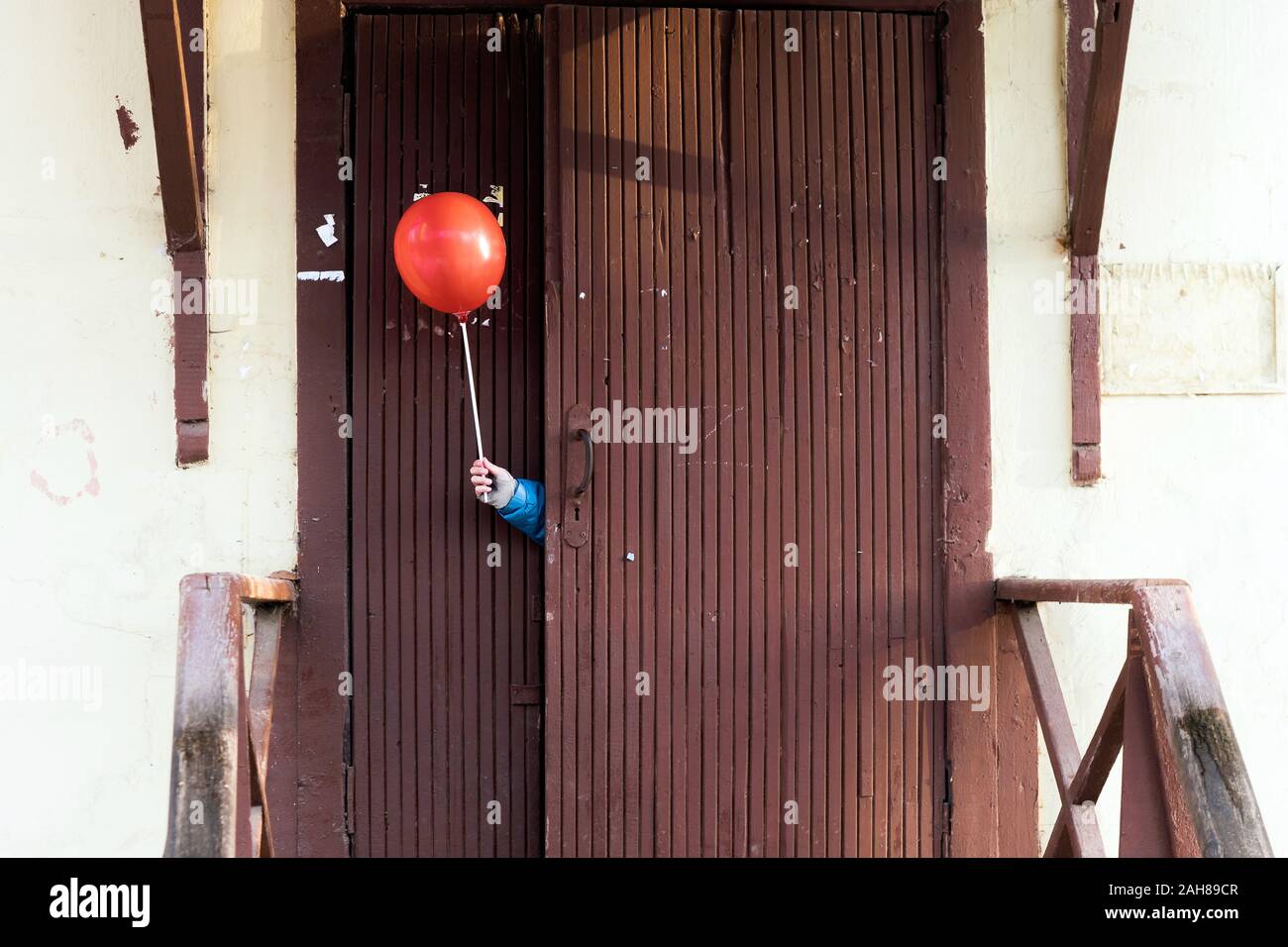 Children's hand in a blue jacket protruding from behind a door with a ...