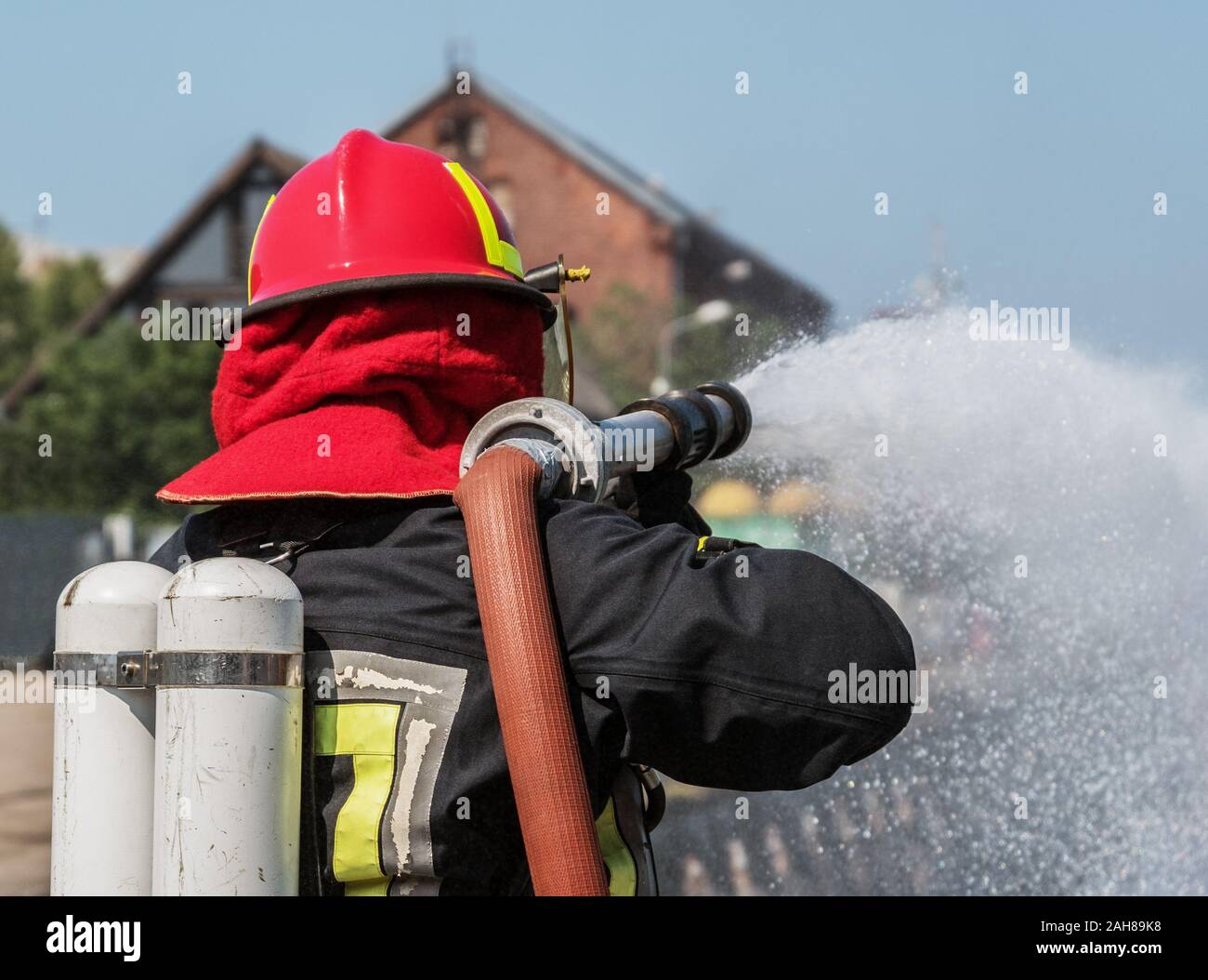 Fireman in uniform and oxygen mask spraying water Stock Photo - Alamy
