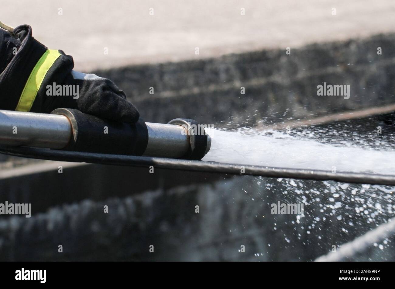 Fireman spraying water from hose Stock Photo - Alamy