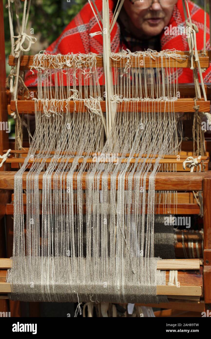 Woman is weaves on a loom outside Stock Photo - Alamy