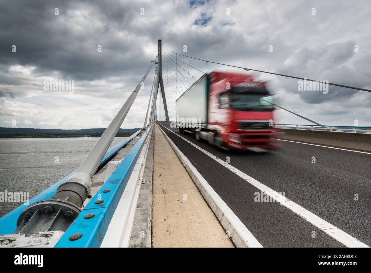 Wide angle view of a french suspension bridge with a red truck passing ...