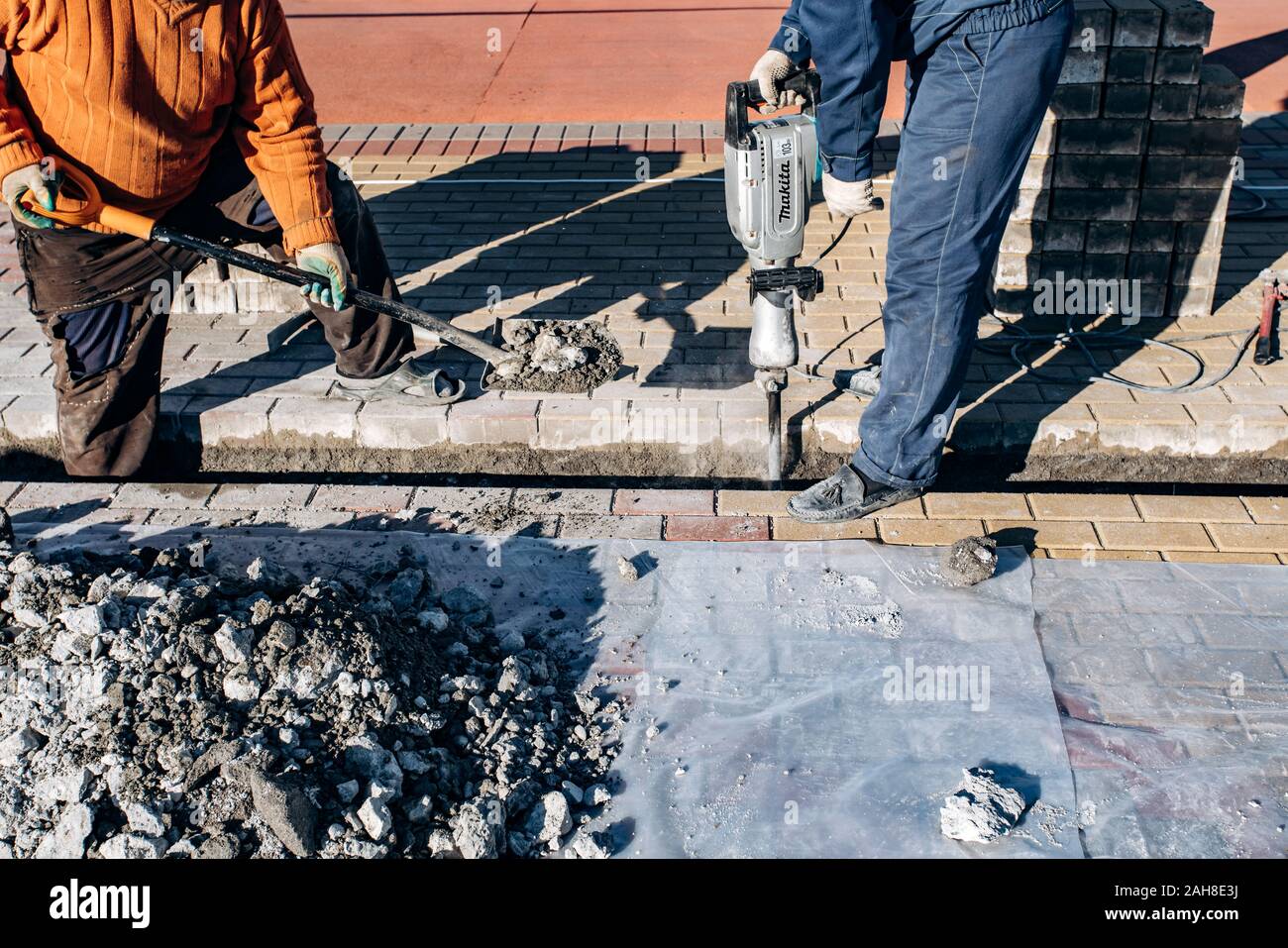 Workers laid paving slabs. Two workers lay paving slabs Stock Photo - Alamy