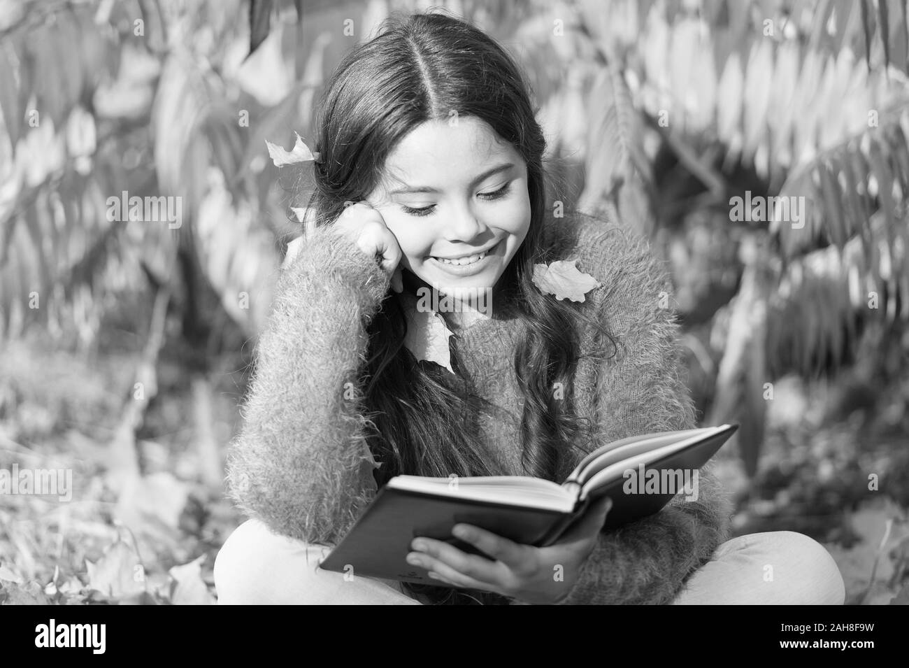 Her hobby is reading. Cute small child reading book on autumn day ...
