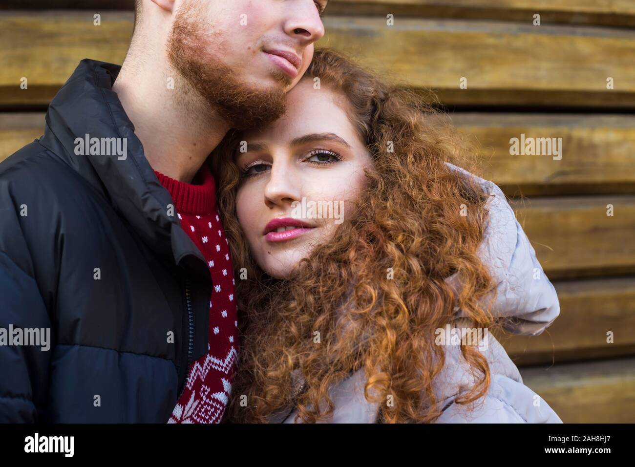 Portrait of a young modern couple in love. Curly girl looking at the camera hugging her ...