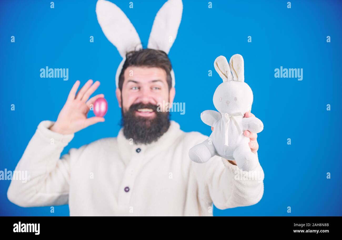 Spring symbols. Hipster with long rabbit ears holding egg laying hare ...