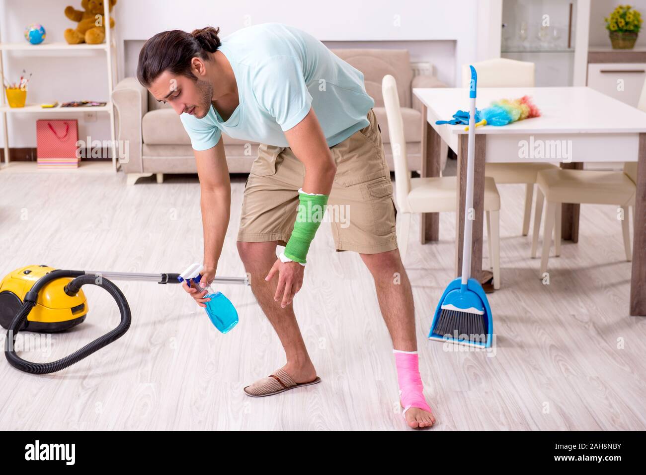 The young injured man cleaning the house Stock Photo - Alamy