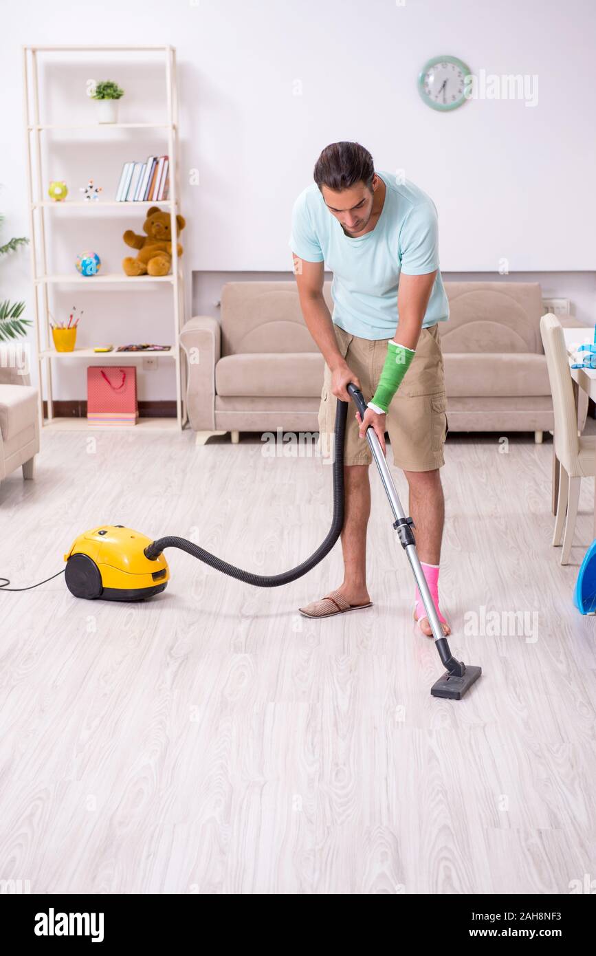 The young injured man cleaning the house Stock Photo - Alamy