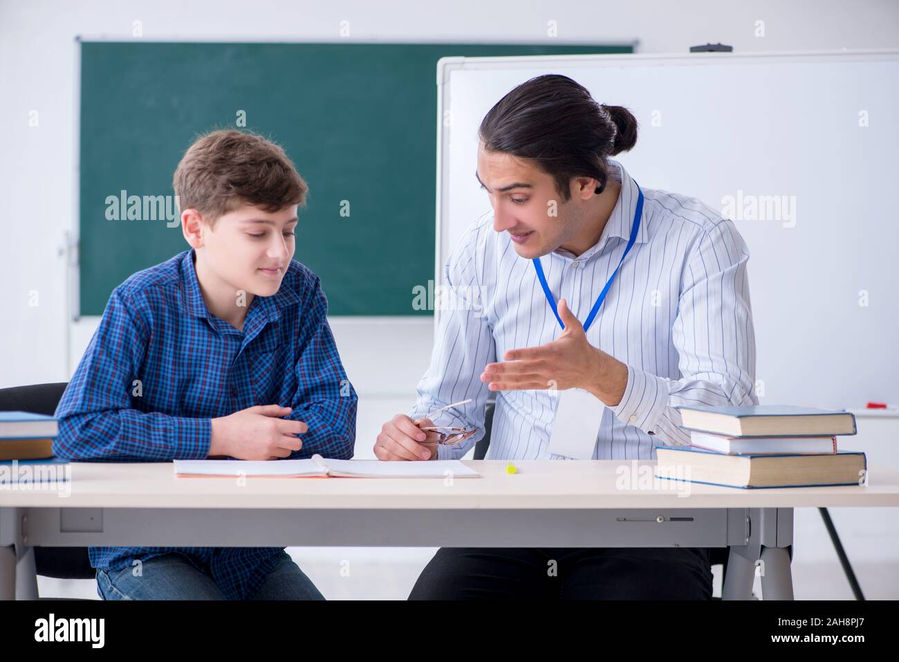 The young male teacher and boy in the classroom Stock Photo - Alamy